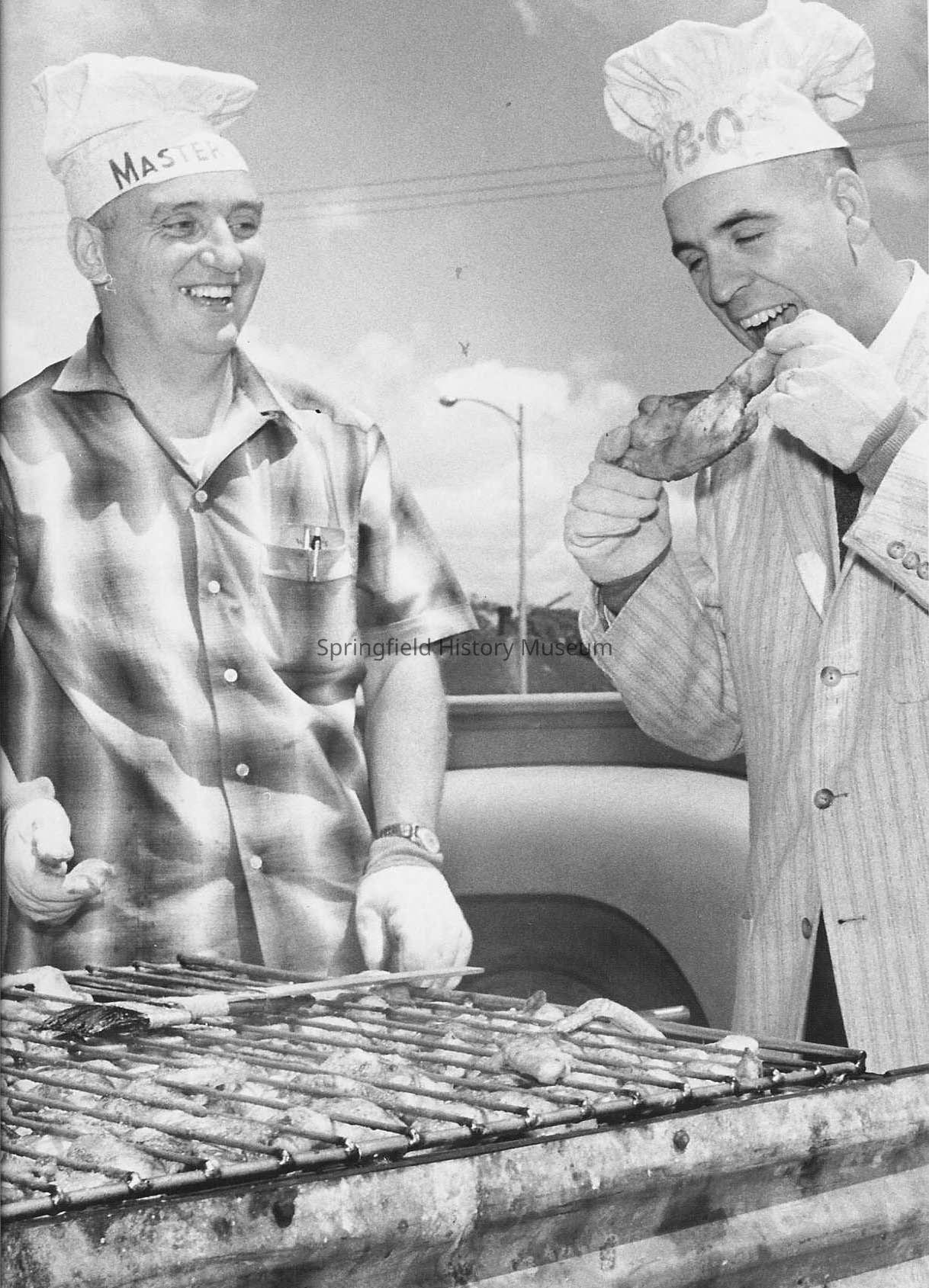 Photograph of two men in chef hats standing at the broiler rack, circa ...