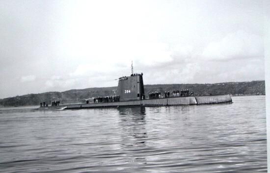 USS Razorback (SS394) entering port with crew at quarters